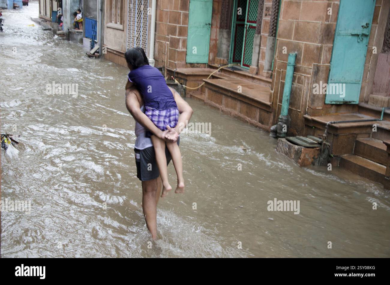 Man carrying daughter on back rain water on street, jodhpur, rajasthan ...