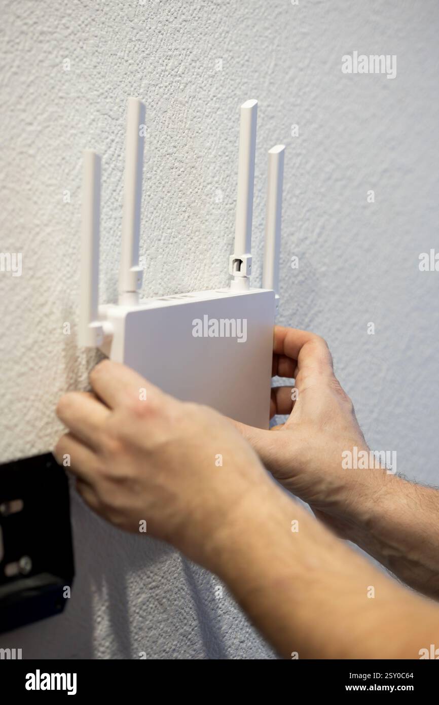 An individual installs a modern WiFi router on the wall, optimizing ...