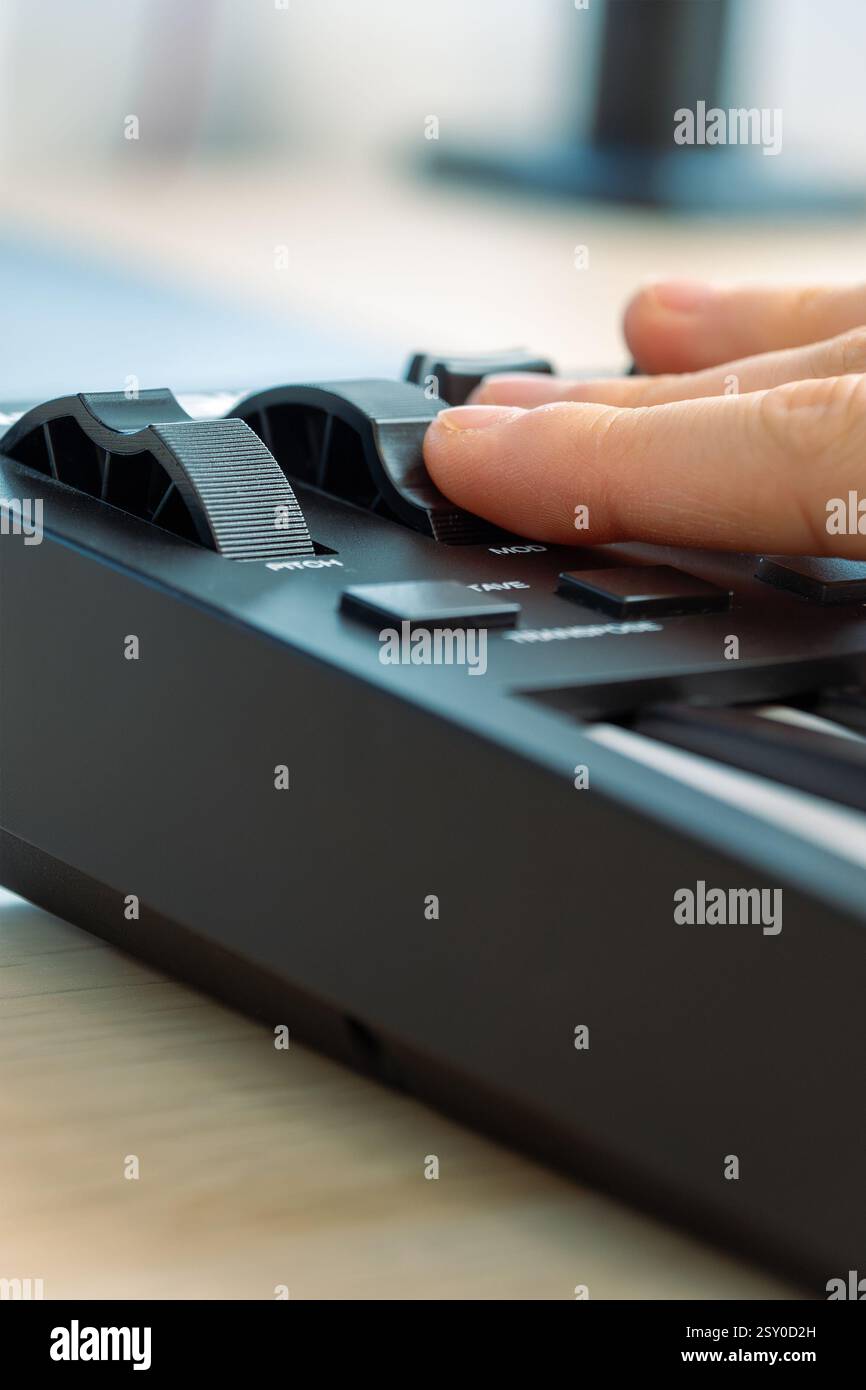 Woman playing MIDI keyboard with control knobs and pads, close-up ...