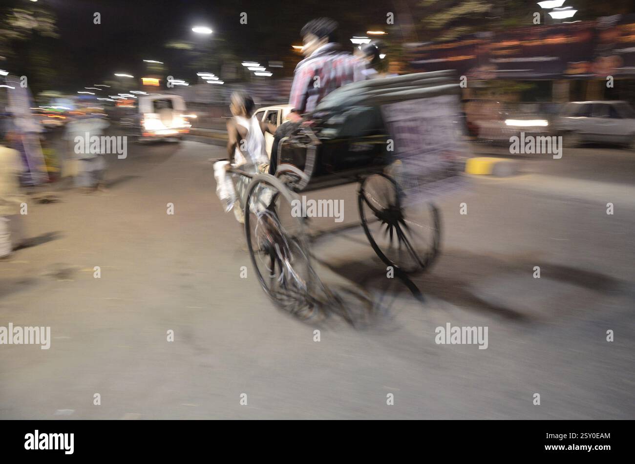 Hand rickshaw puller with passenger is running on road at Kolkata India ...