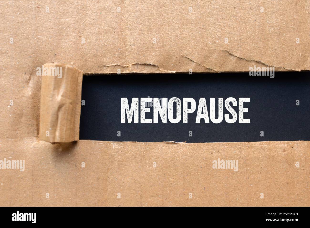 Menopause message written on ripped torn cardboard paper on black ...
