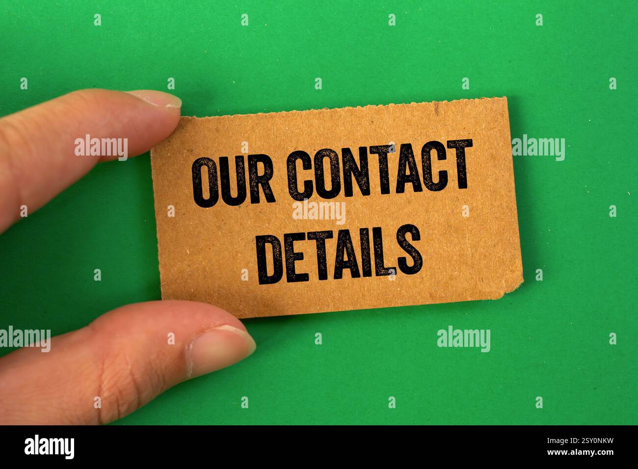 Our contact details message written on cardboard paper on green ...