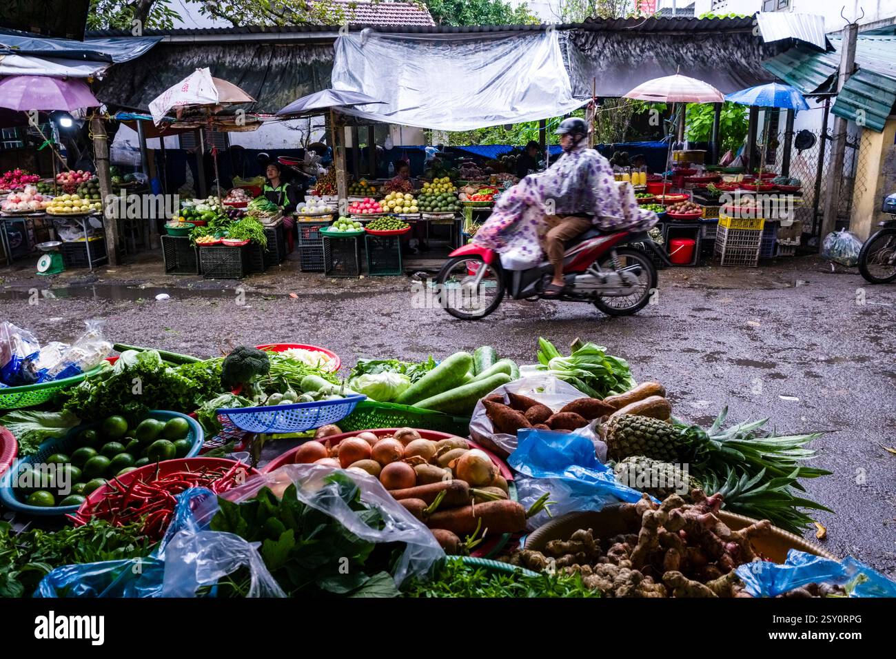 A man on a motorbike rides past one of the many street markets in the ...