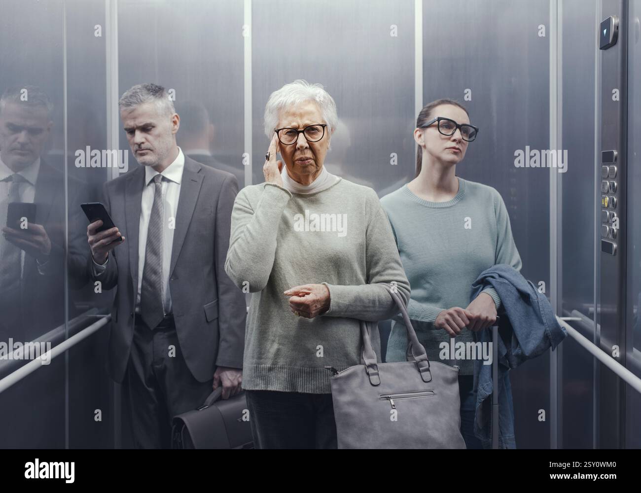 Confused senior woman standing inside a crowded elevator, she has a ...
