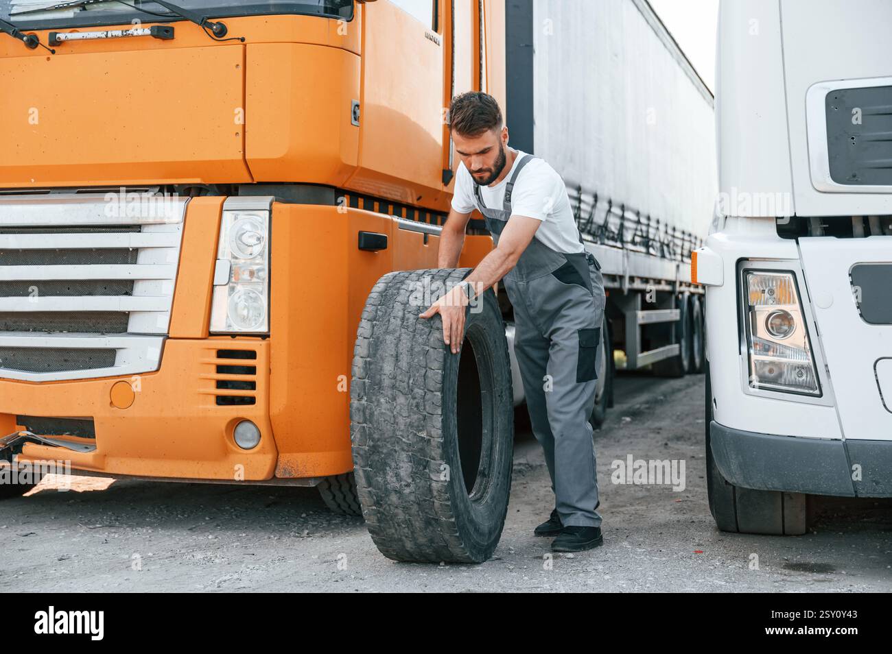 Changing the tire. Man in unifrom doing service for big truck vehicle ...