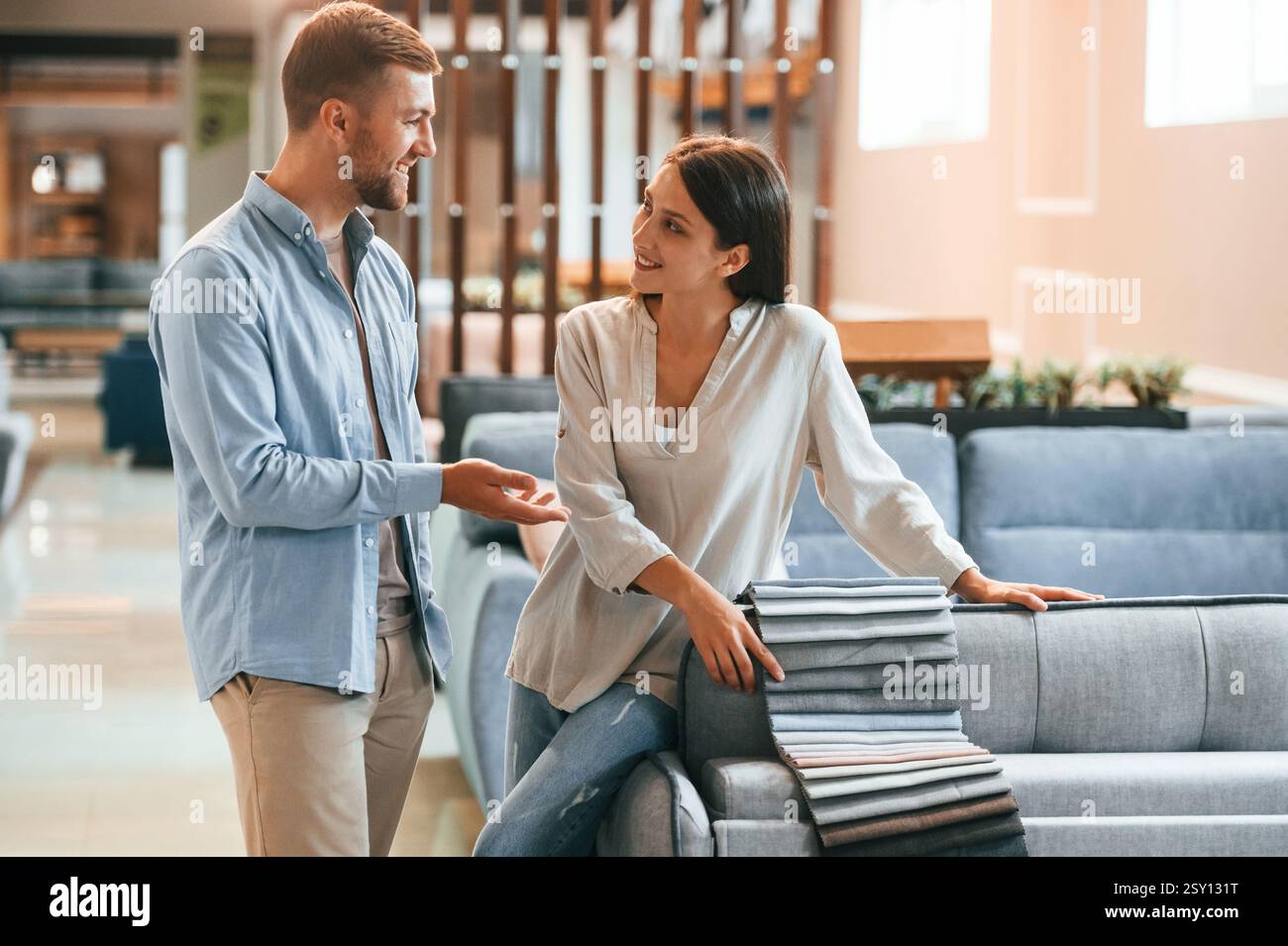 Big choice of colors and materials. Couple choosing the sofa and bed in ...