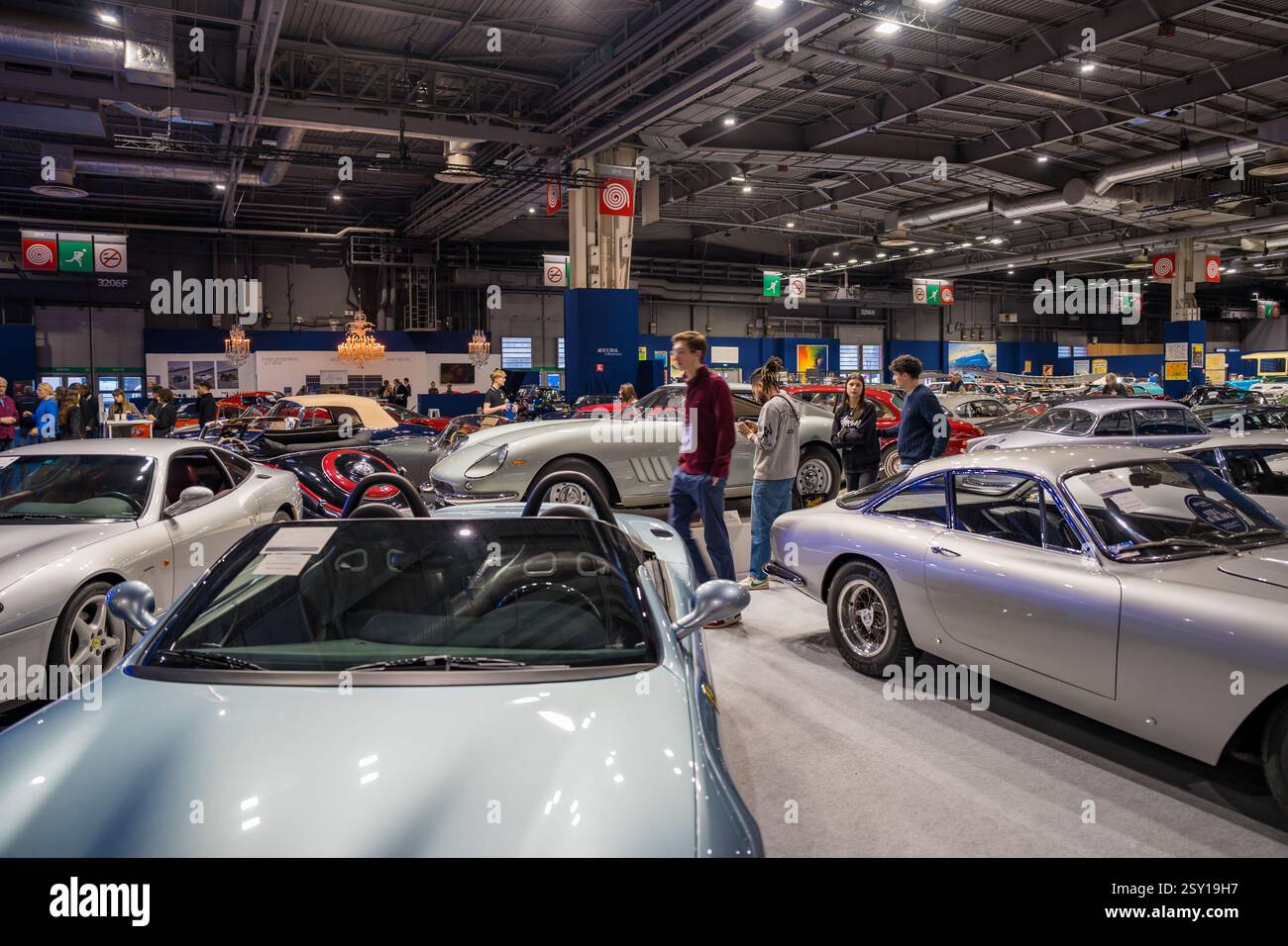 Classic car enthusiasts explore a vibrant auto show in a spacious venue ...