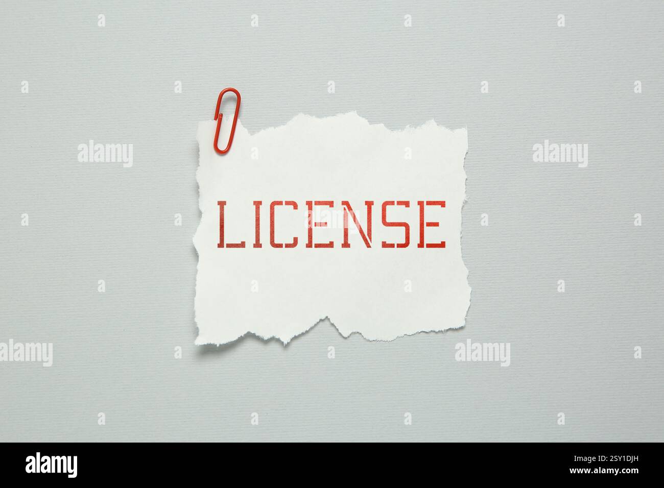 Piece of paper with word License and paperclip on white background, top ...