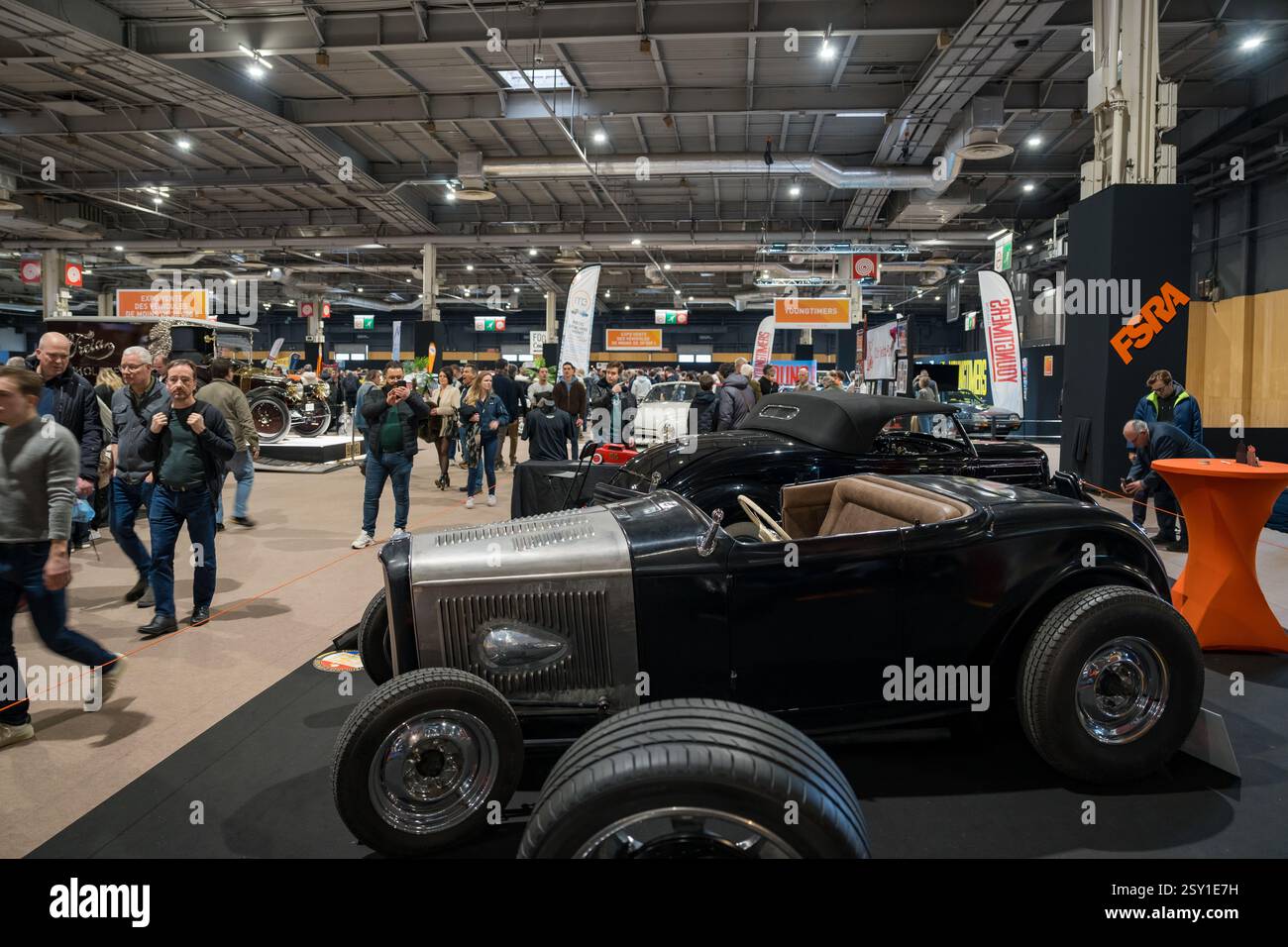 Vintage car exhibit attracts automotive enthusiasts in lively indoor ...