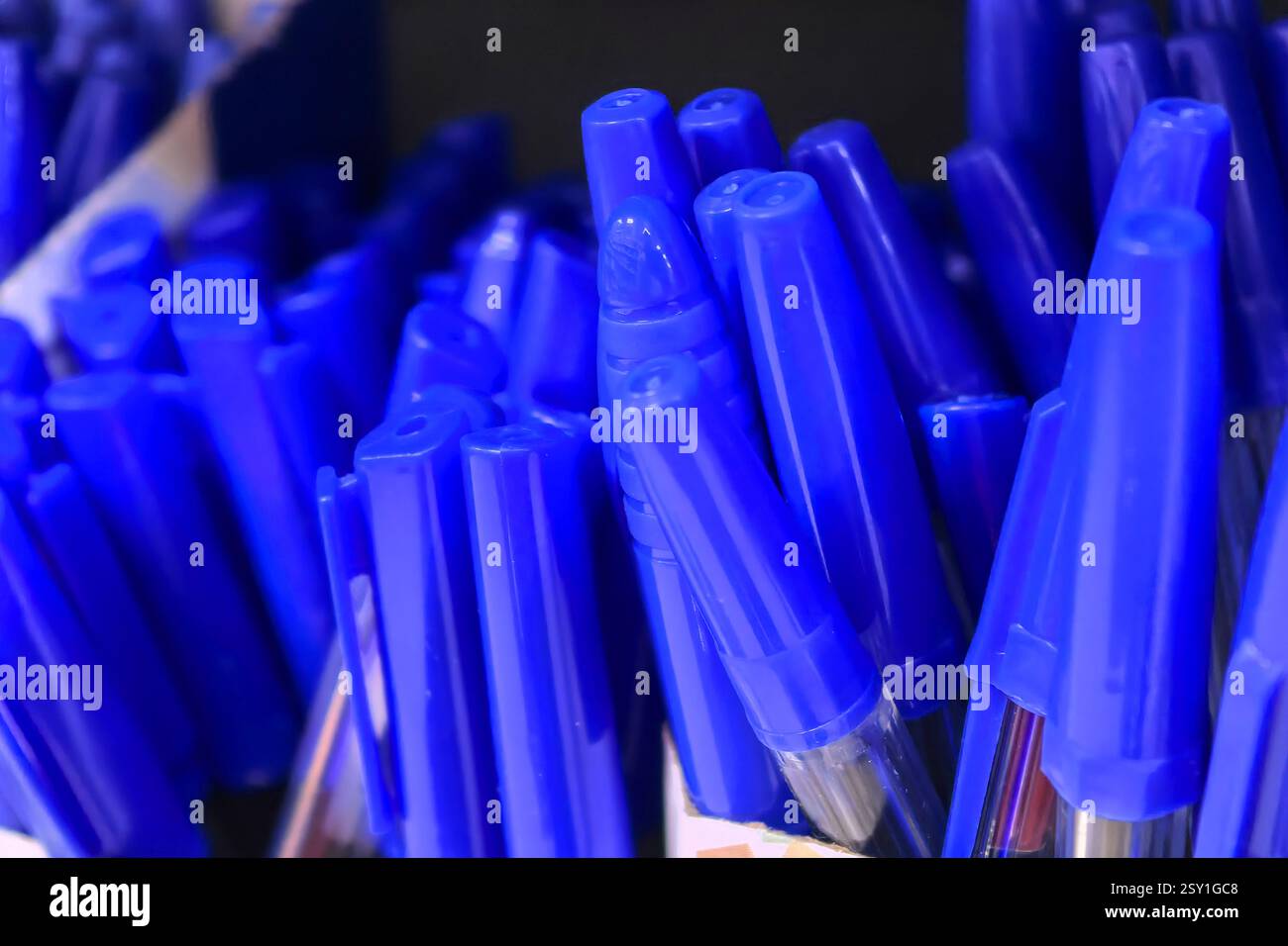 A multitude of blue pens is tightly packed on the shelf of an office ...