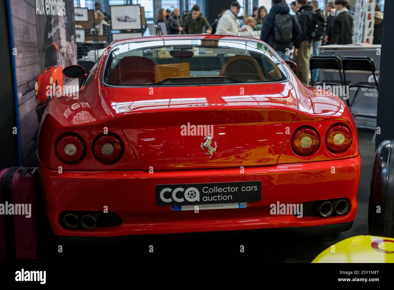 Red sports car on display at a lively collector car auction in a ...