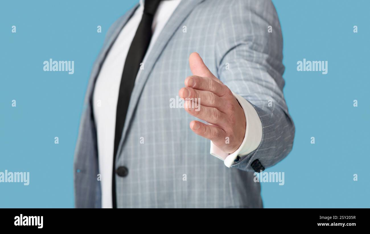 Untrecognizable young businessman offering hand for handshake on blue ...