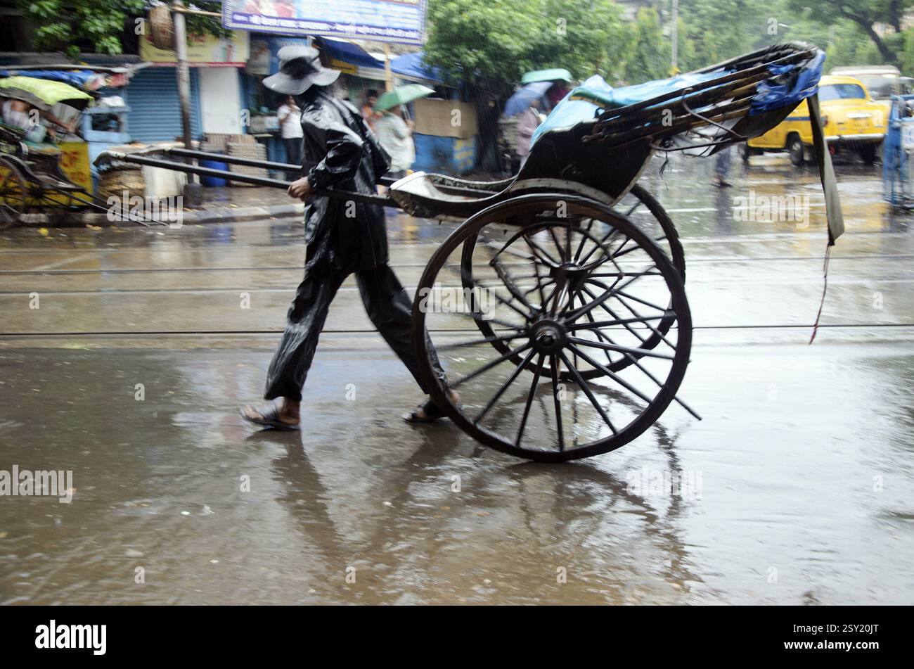 Man in raincoat pulling Hand Rickshaw on street in Kolkata at West ...