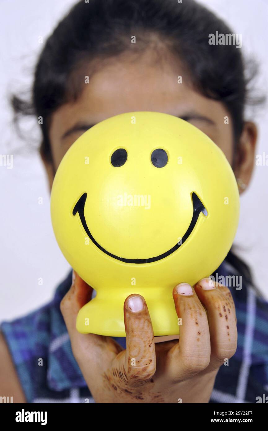 Girl child with smiley face piggy bank toy, India, Asia, MR#682W, Asia ...