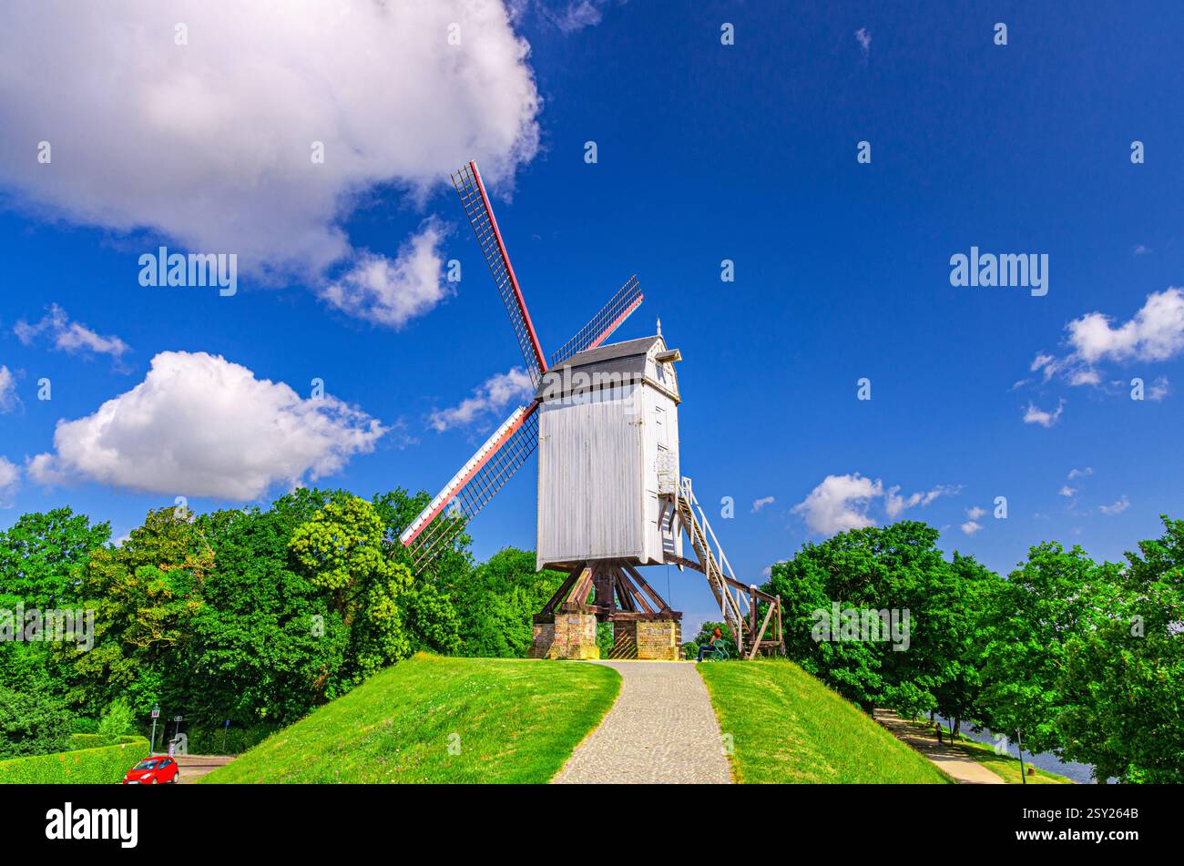 Traditional old windmill on green hill in Brugge city, blue sky white ...