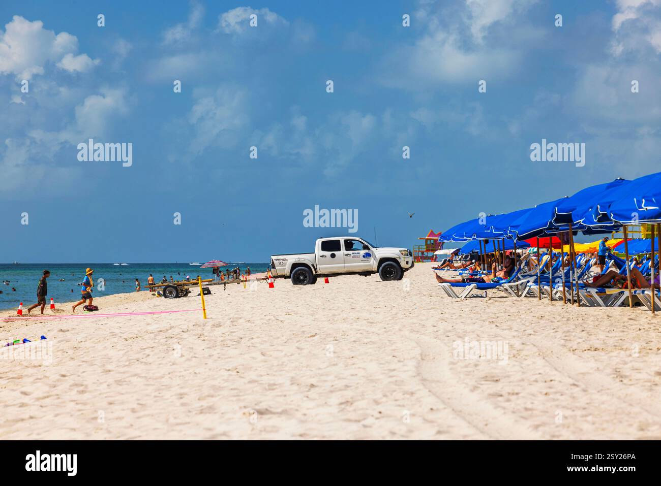 Miami Beach truck with trailer transporting jet skis near sunbathers ...