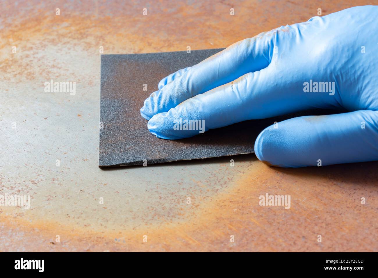 Sanding rust off sheet steel with fine grit wet and dry sandpaper ...