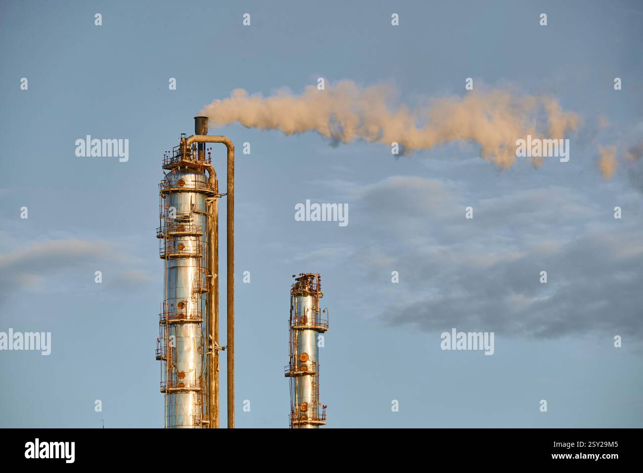 Industrial distillation column at a chemical plant releasing vapor ...