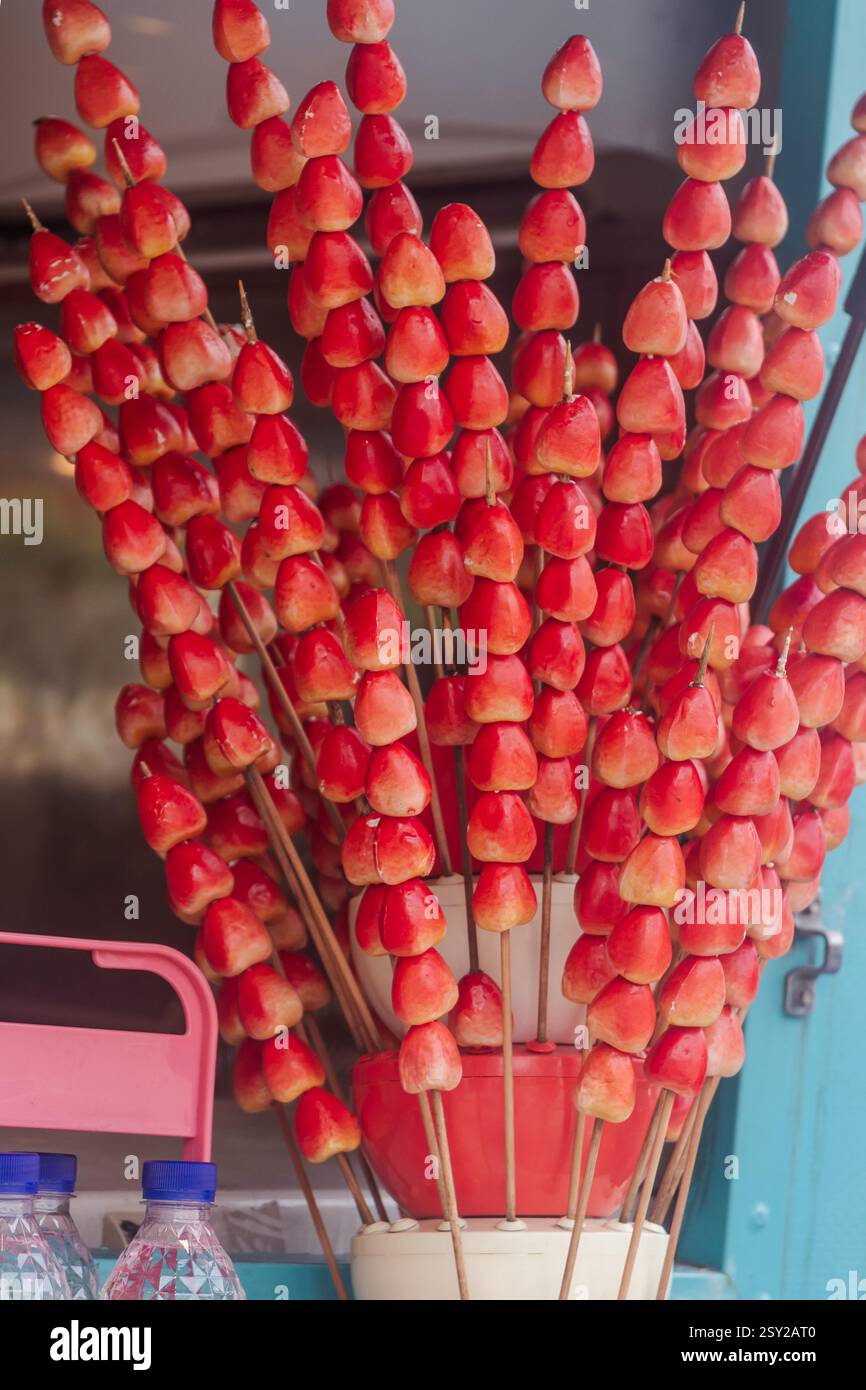 A skewer of candied strawberries coated in a glossy, hardened sugar ...