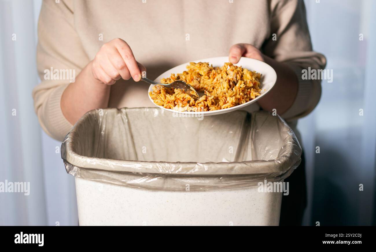 Woman throwing away food leftovers into garbage bin trash. Scraping ...