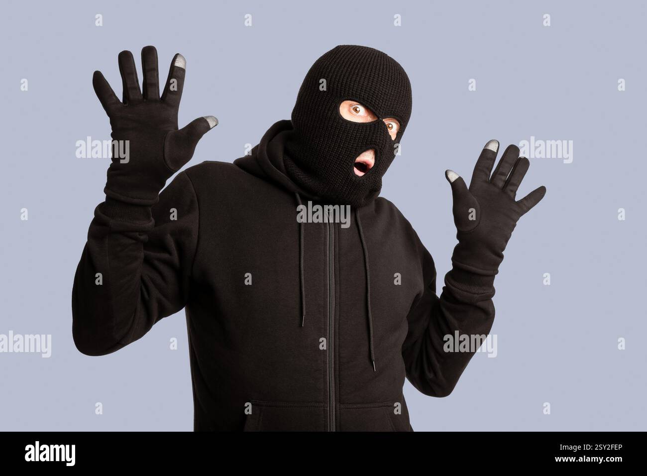 Arrested masked thief with raised arms isolated over white wall Stock ...