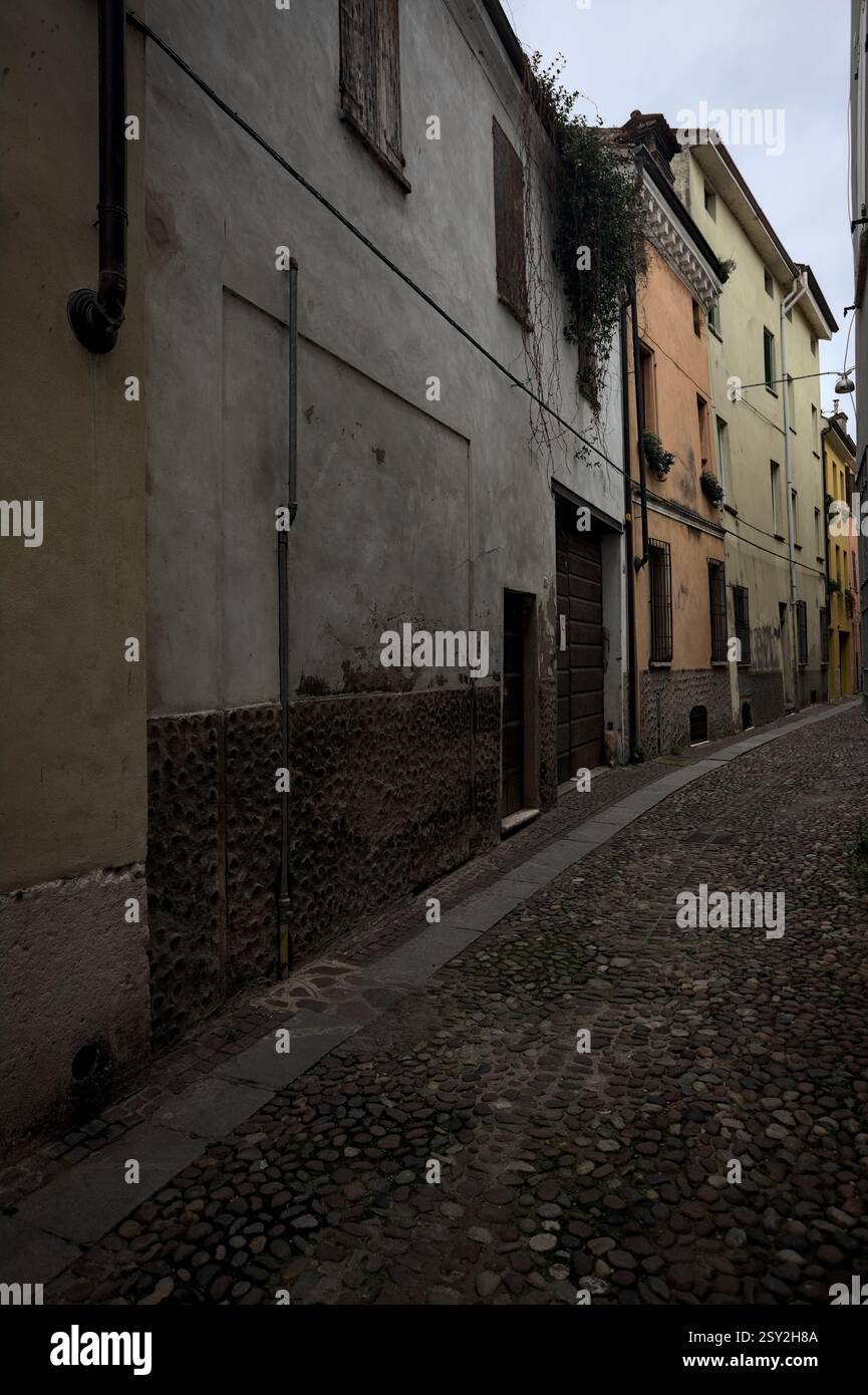 Very narrow cobbled street in the shade that makes a bend at the end in ...