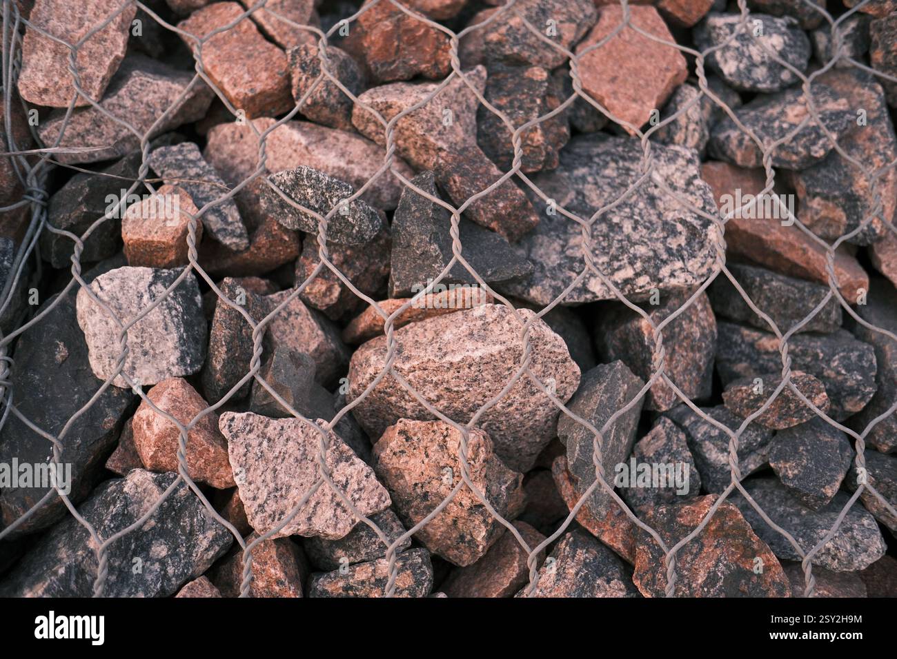 Rocks enclosed in metal wire chain-link fencing mesh, protection from ...