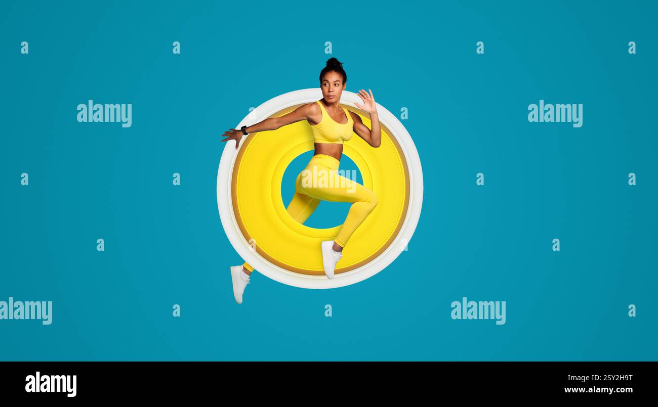 Determined African American fitness woman jumps against blue studio ...