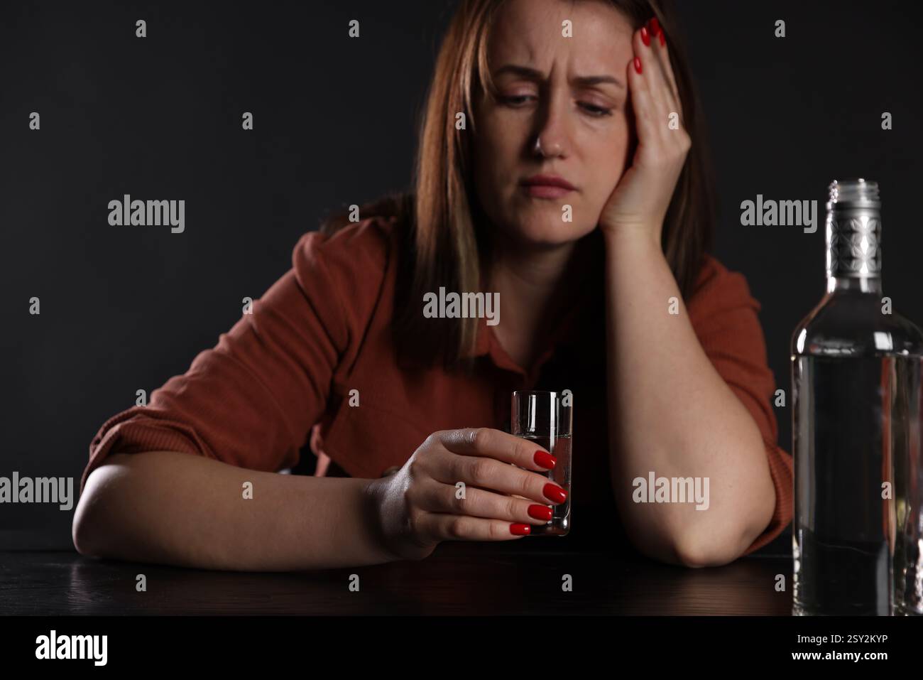 Alcohol addiction. Miserable woman with vodka at table in dark Stock ...