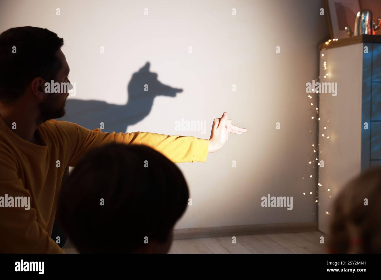 Man making hand gesture like llama while performing shadow play to his ...