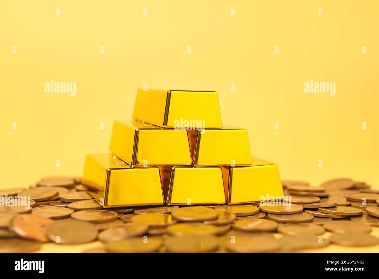 Gold bars and coins on pale yellow background, closeup Stock Photo - Alamy