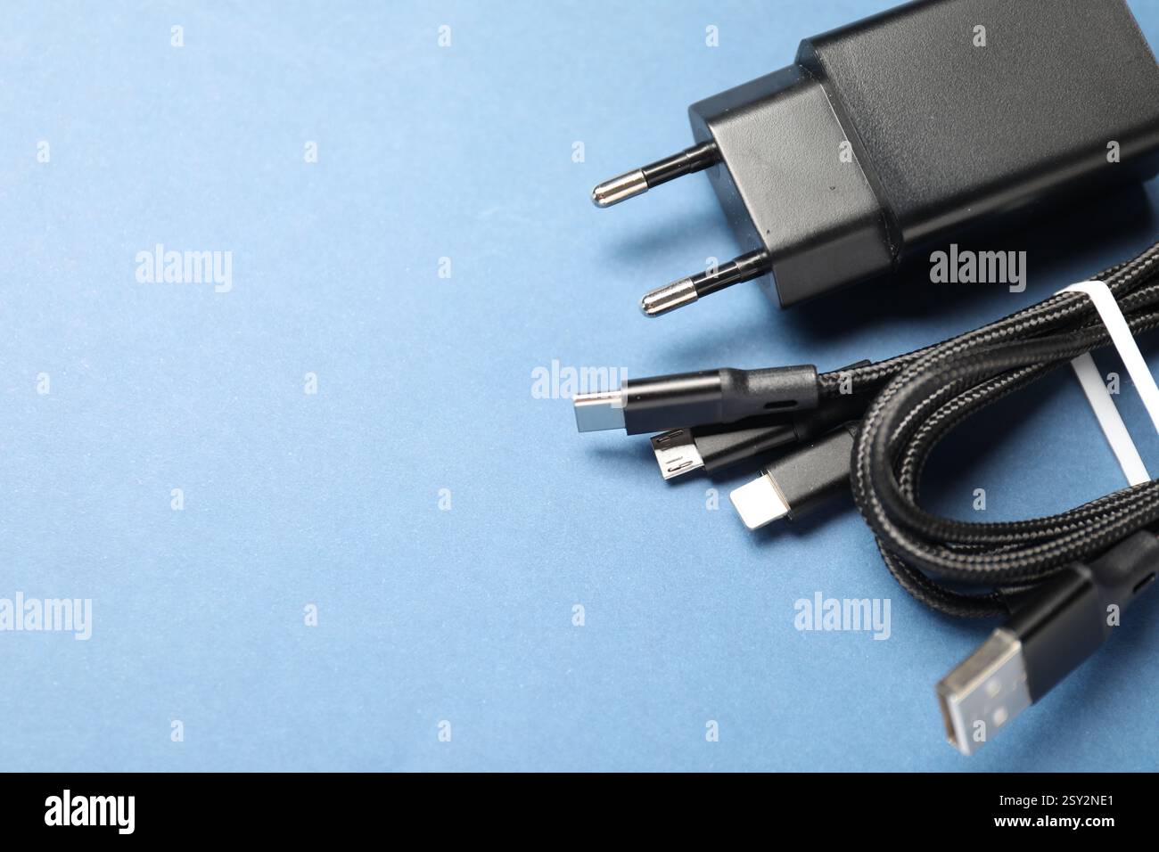USB power adapter and triple charge cable on light blue background ...
