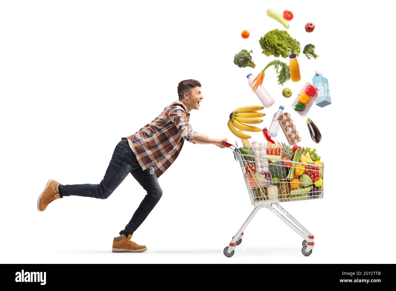 Happy young man running with a full shopping cart and falling groceries ...