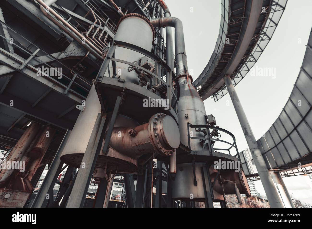 Industrial metal structure with large cylindrical tanks, pipes, valves, and railings. Rusted ...