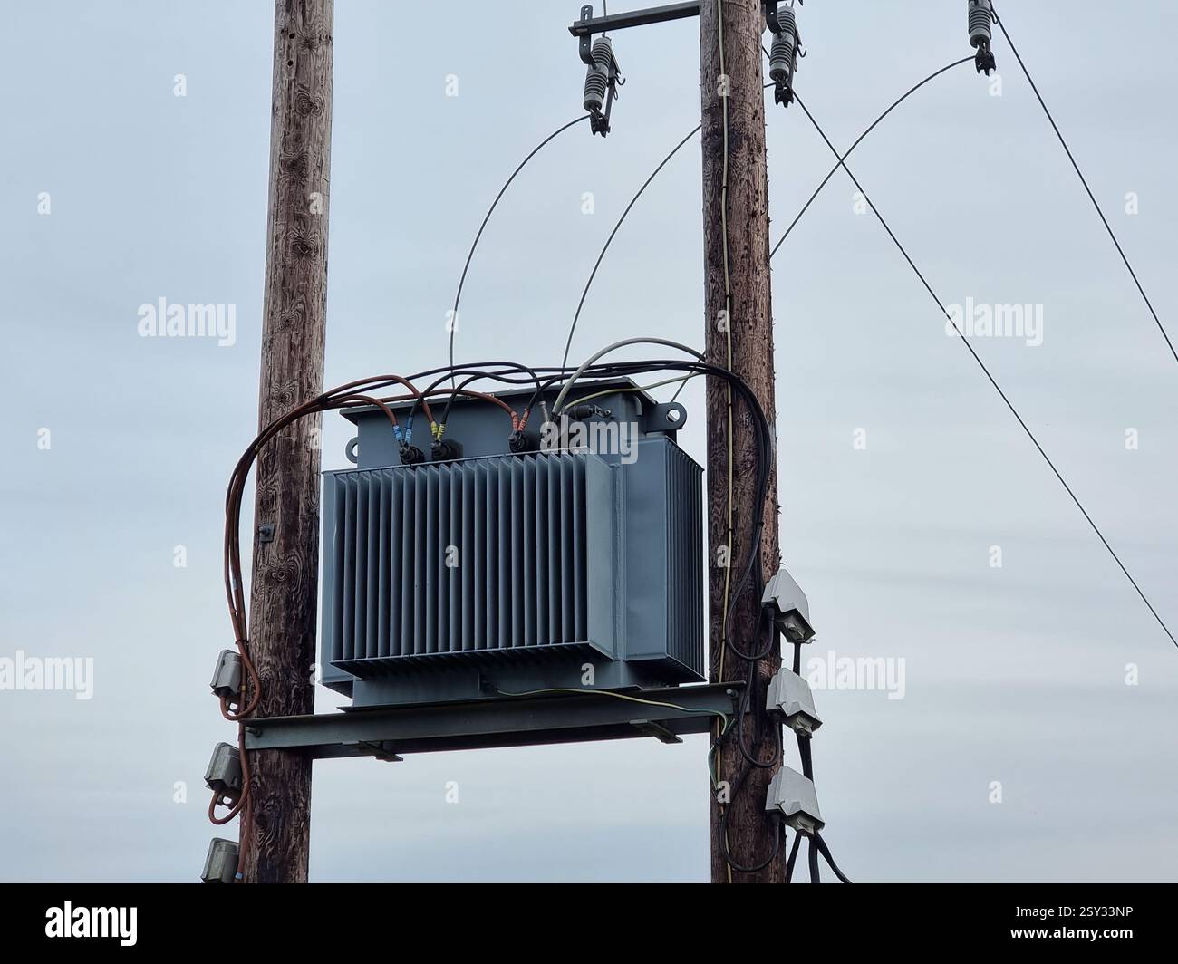 An electrical transformer mounted on a platform between two wooden ...