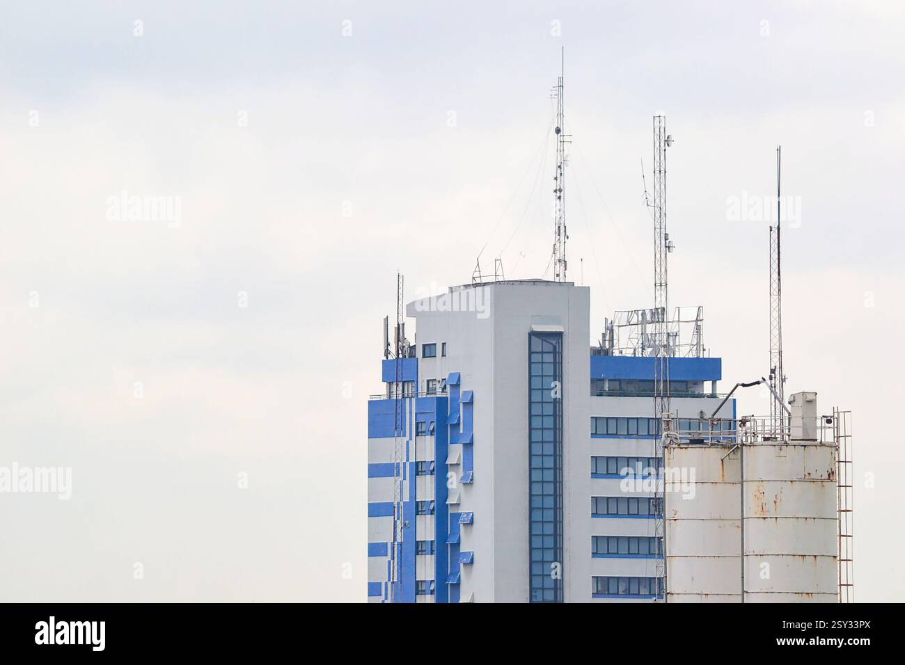 A modern high rise building with blue and white facade, rooftop ...