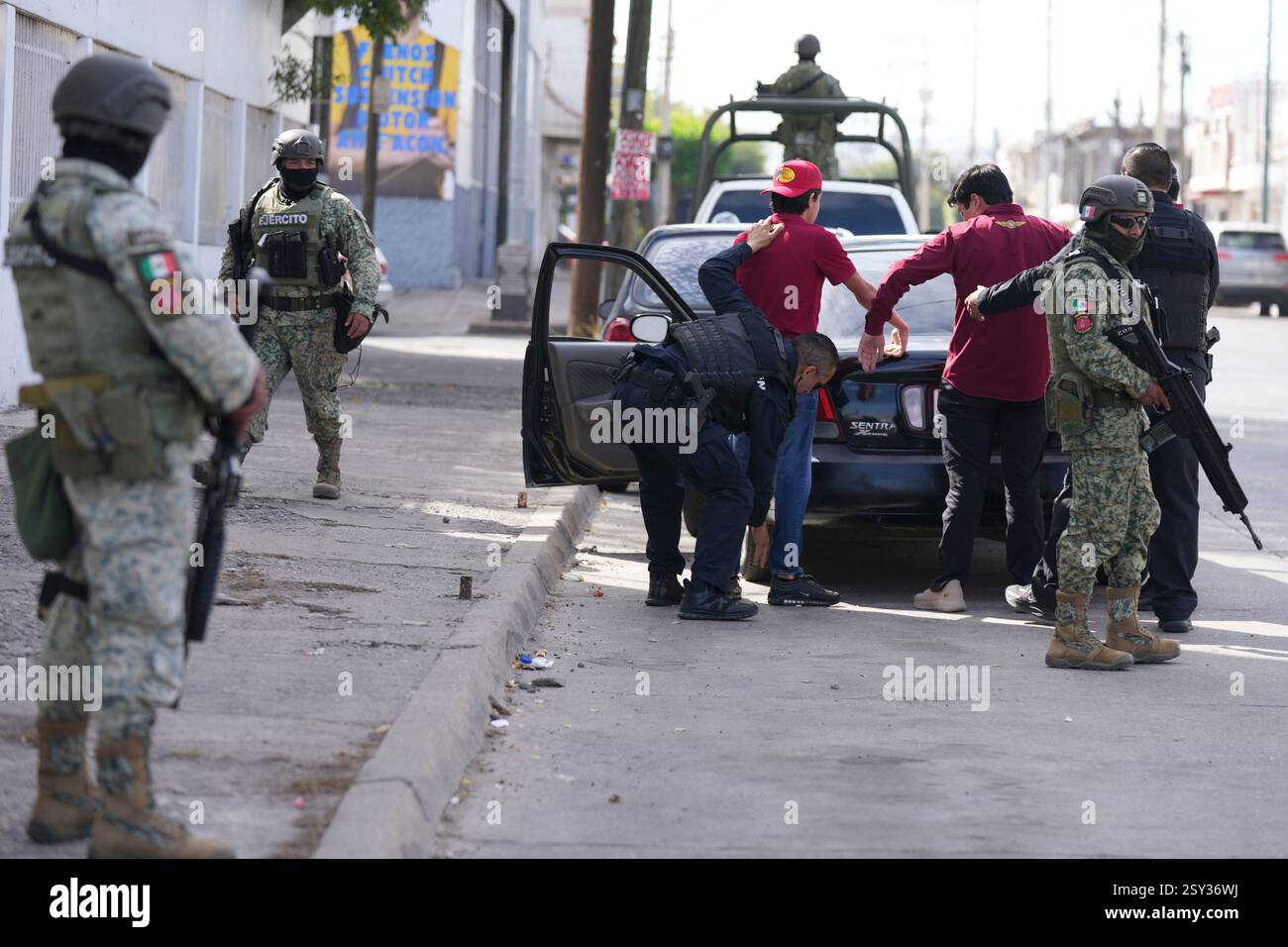 Police officers and soldiers inspect drivers at a checkpoint in ...