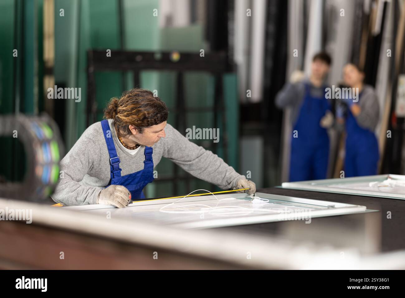 Man employee in blue overall measures given length of plastic material ...