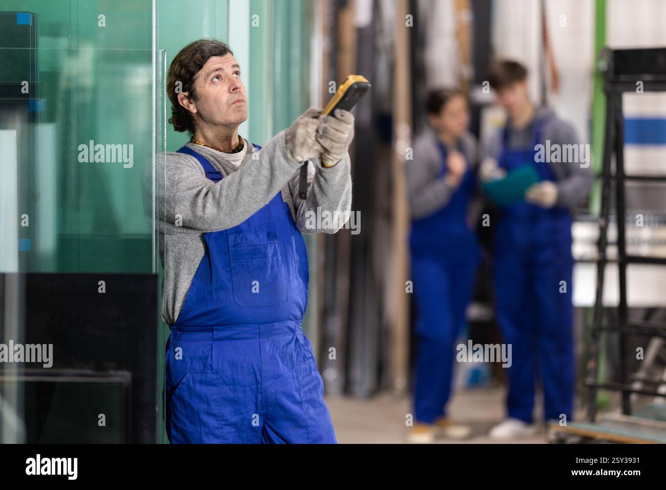 Man employee in blue overall uses remote control to move lifting ...