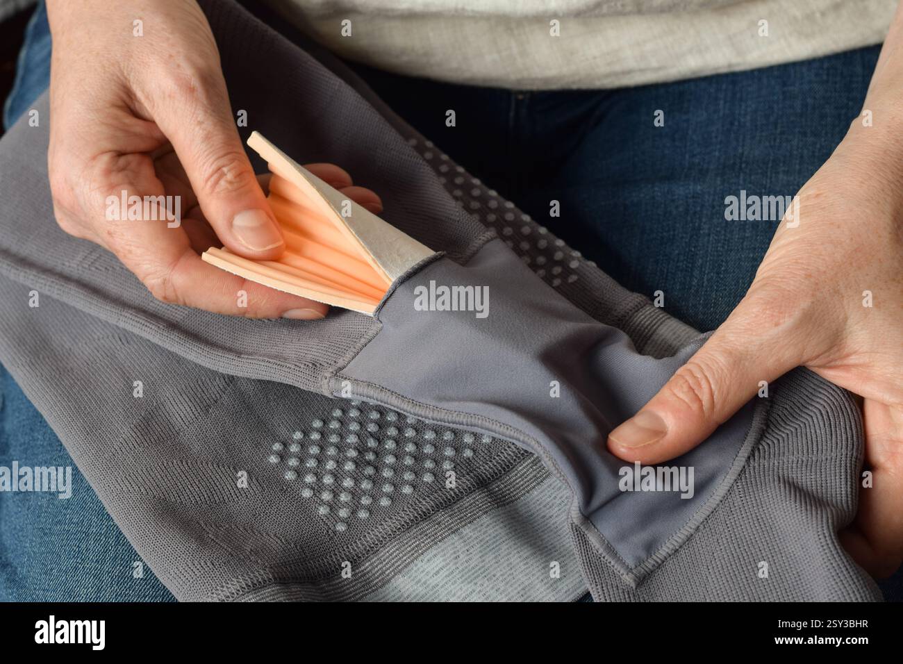 Closeup woman inserting ribbed foam pads into compression garment ...