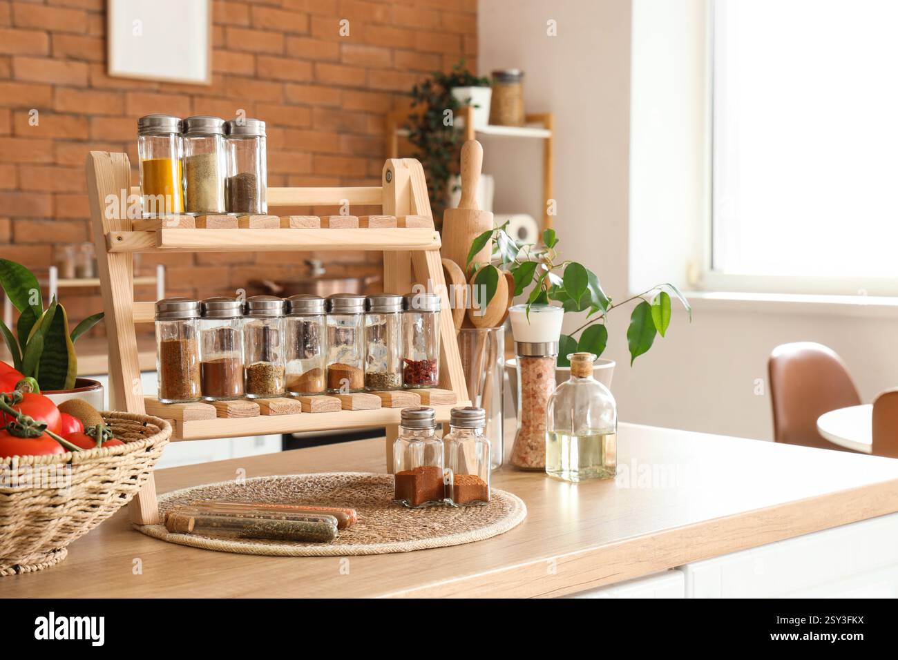 Stand with different spices, utensils and plant on table in kitchen ...