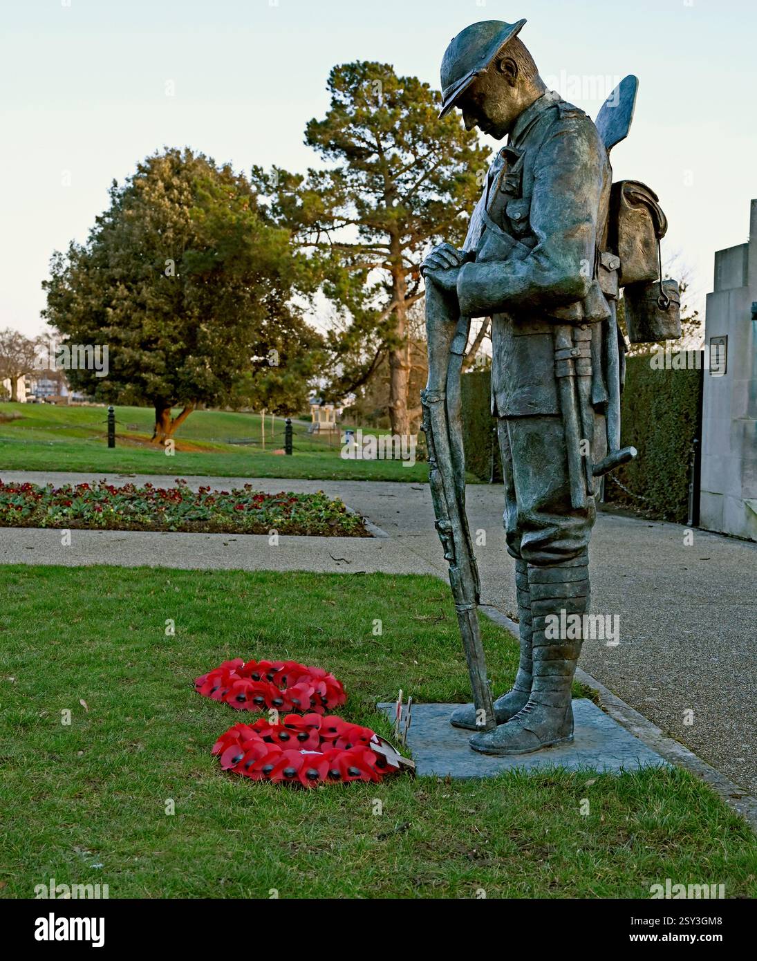A bronze sculpture of a First World War Soldier - two poppy wreaths at ...