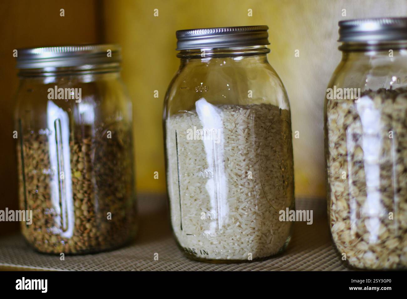 Three glass jars, each sealed with metal lids, are neatly lined up on a ...