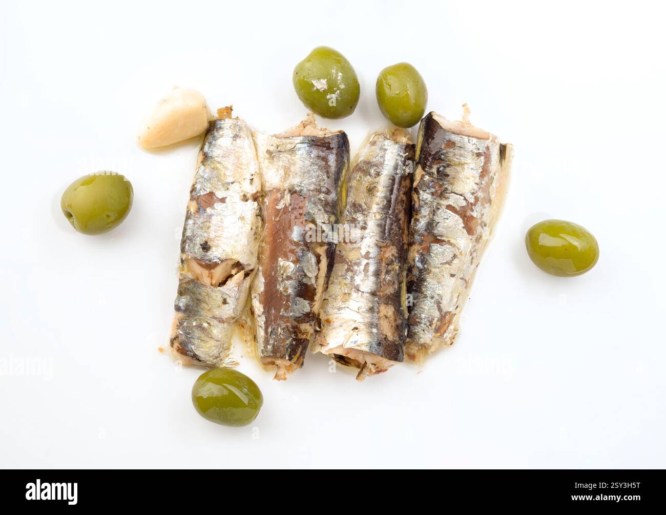 Sardines preserved in olive oil are arranged alongside green olives ...