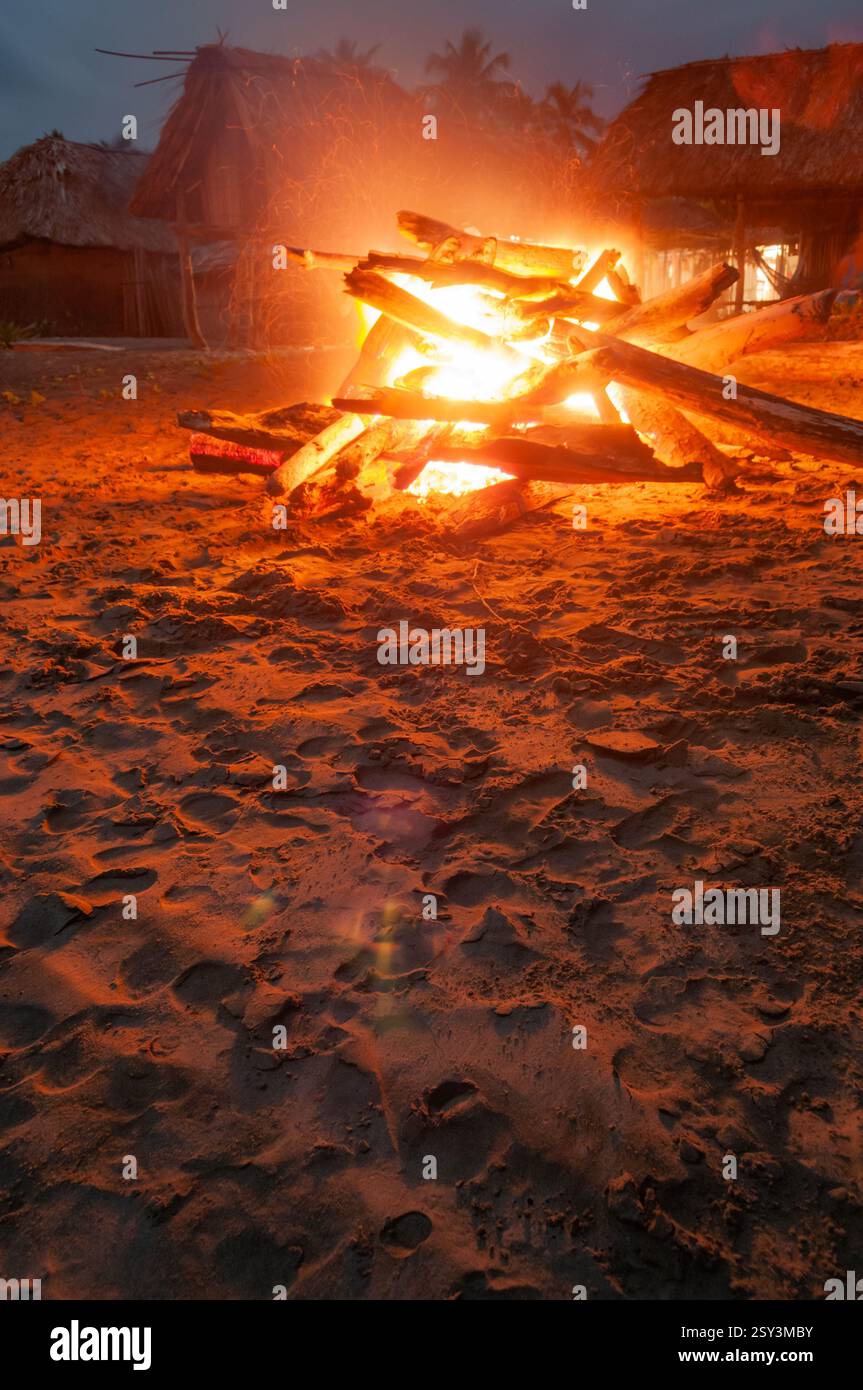 Small campfire with gentle flames beside the sea with stars in the sky ...