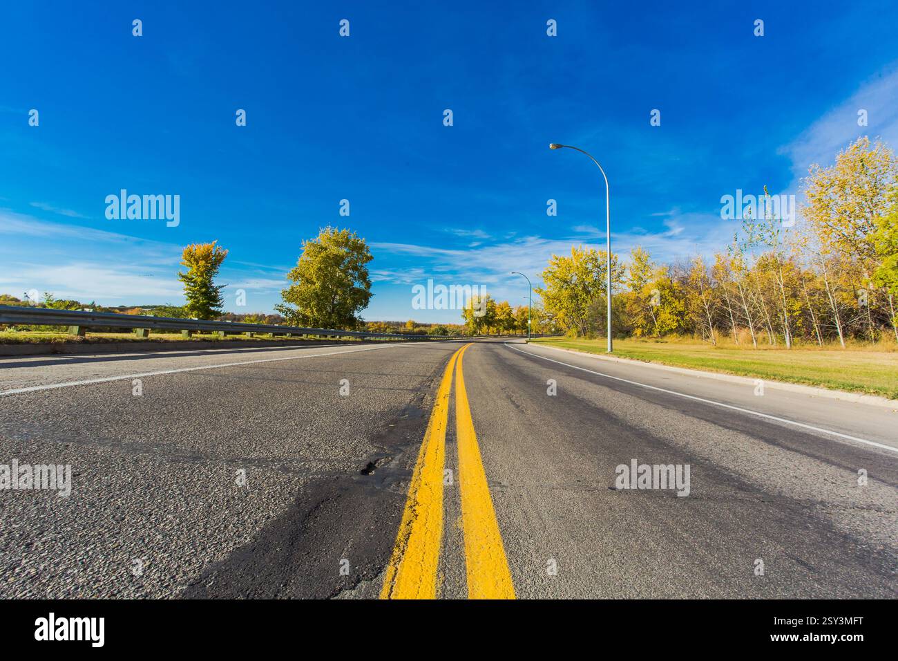 Road with a yellow line down the middle. The road is empty. The sky is ...
