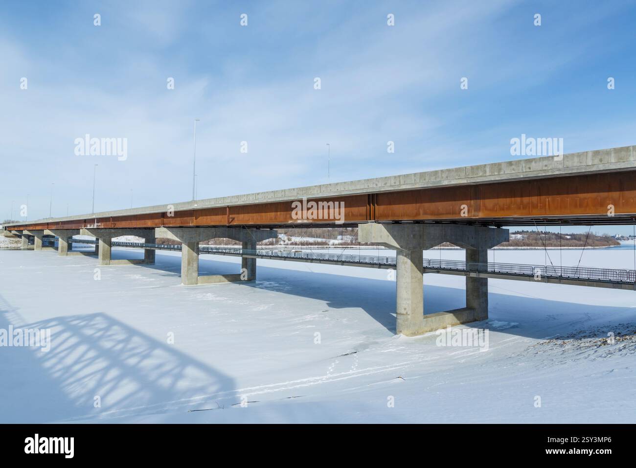 Bridge over a river with snow on the ground. The bridge is long and has ...