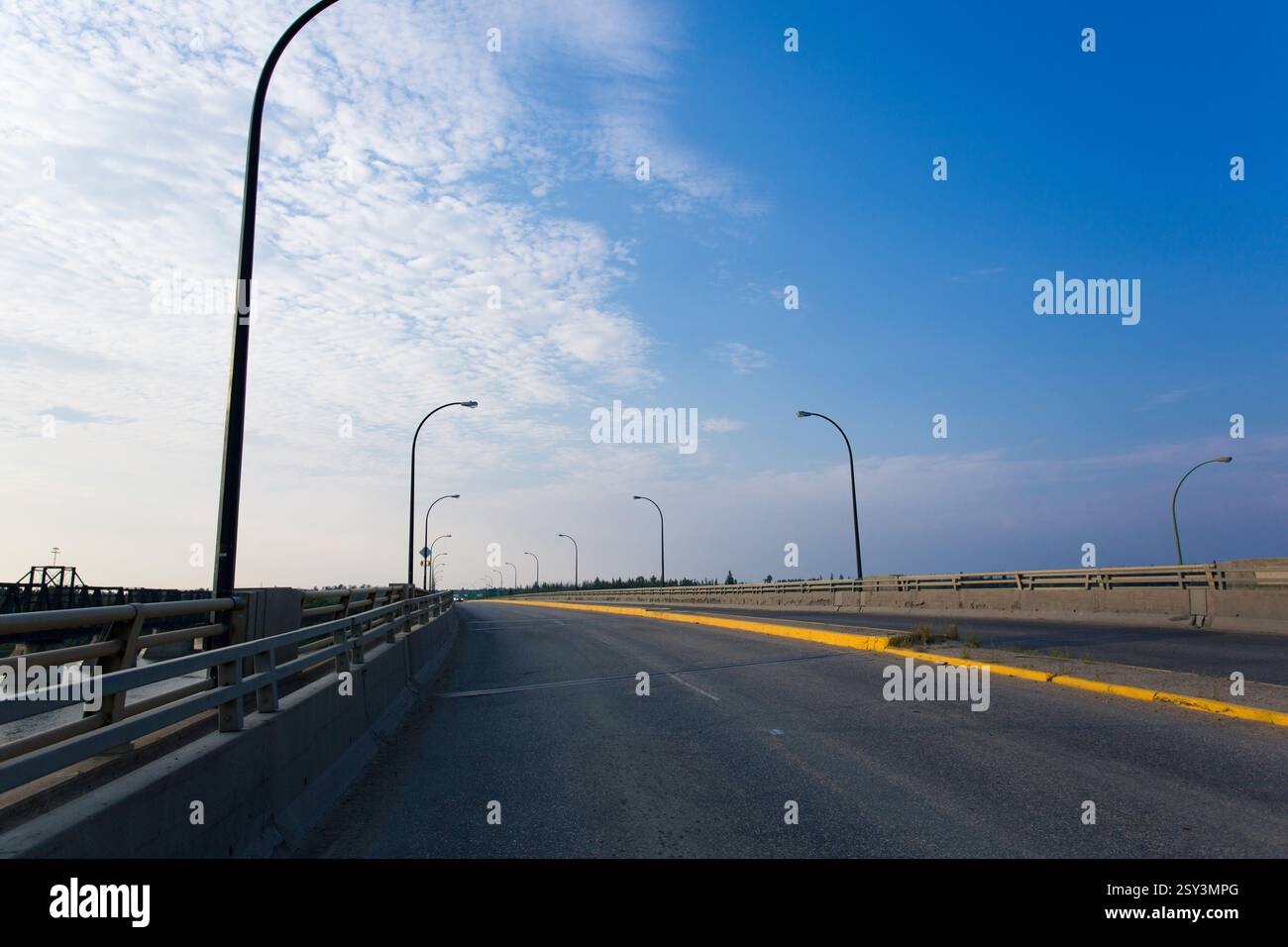 Long, empty road with a blue sky above. There are no cars on the road ...