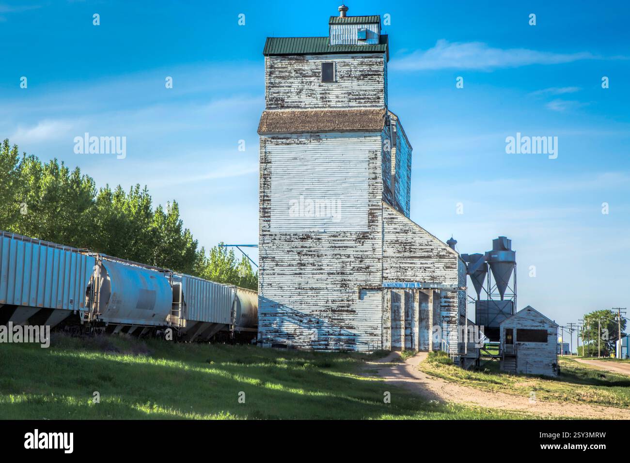 Train is pulling a car full of grain. The train is on a track next to a ...