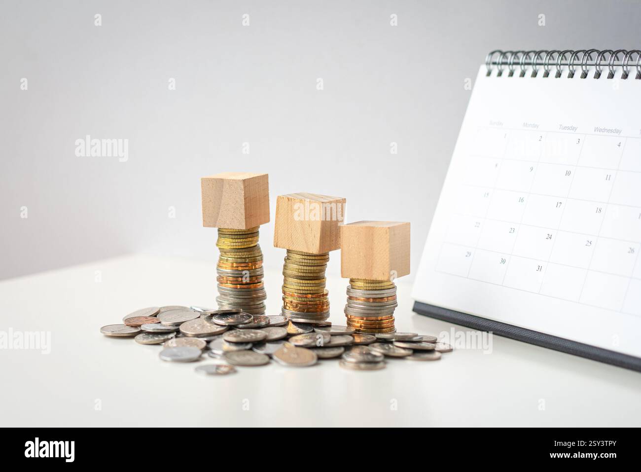 Three toy blocks on top of coins, stacked and lying on table. Next to ...
